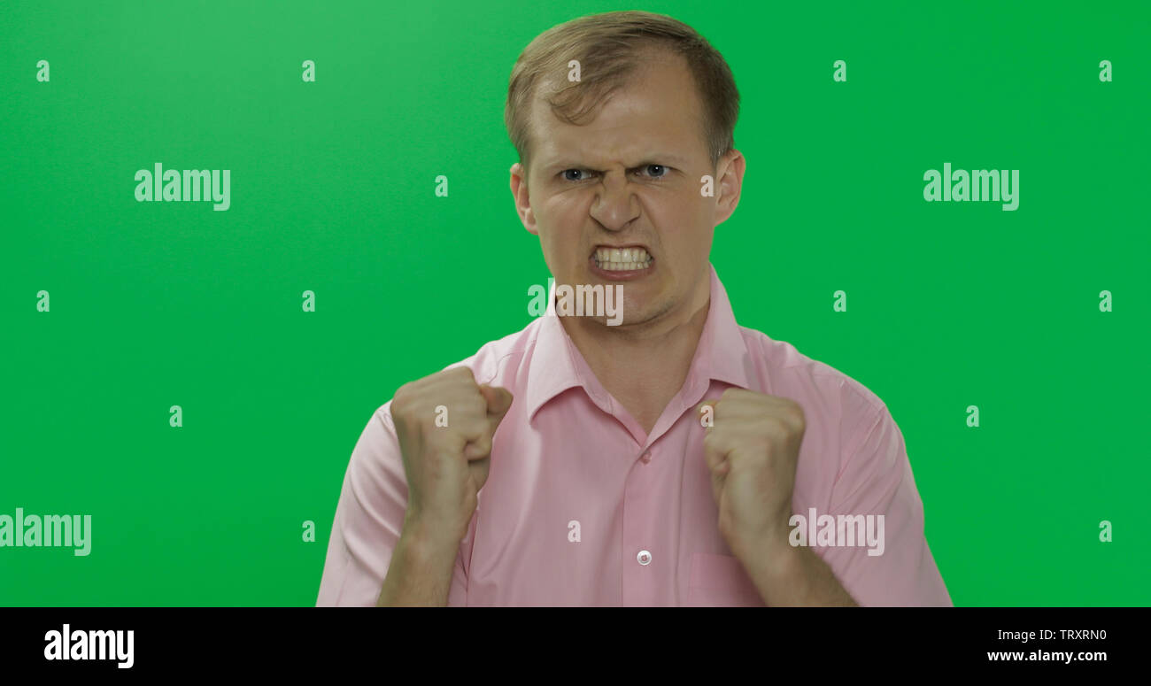 Angry aggressive handsome young man in pink shirt nervous and can not ...