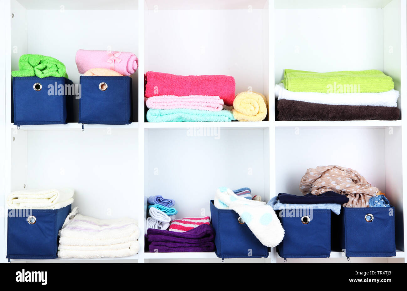Blue textile boxes with towels and clothes in white shelves Stock Photo ...