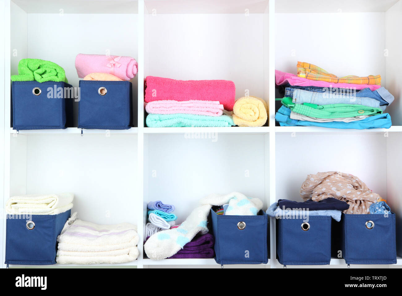 Blue textile boxes with towels and clothes in white shelves Stock Photo ...