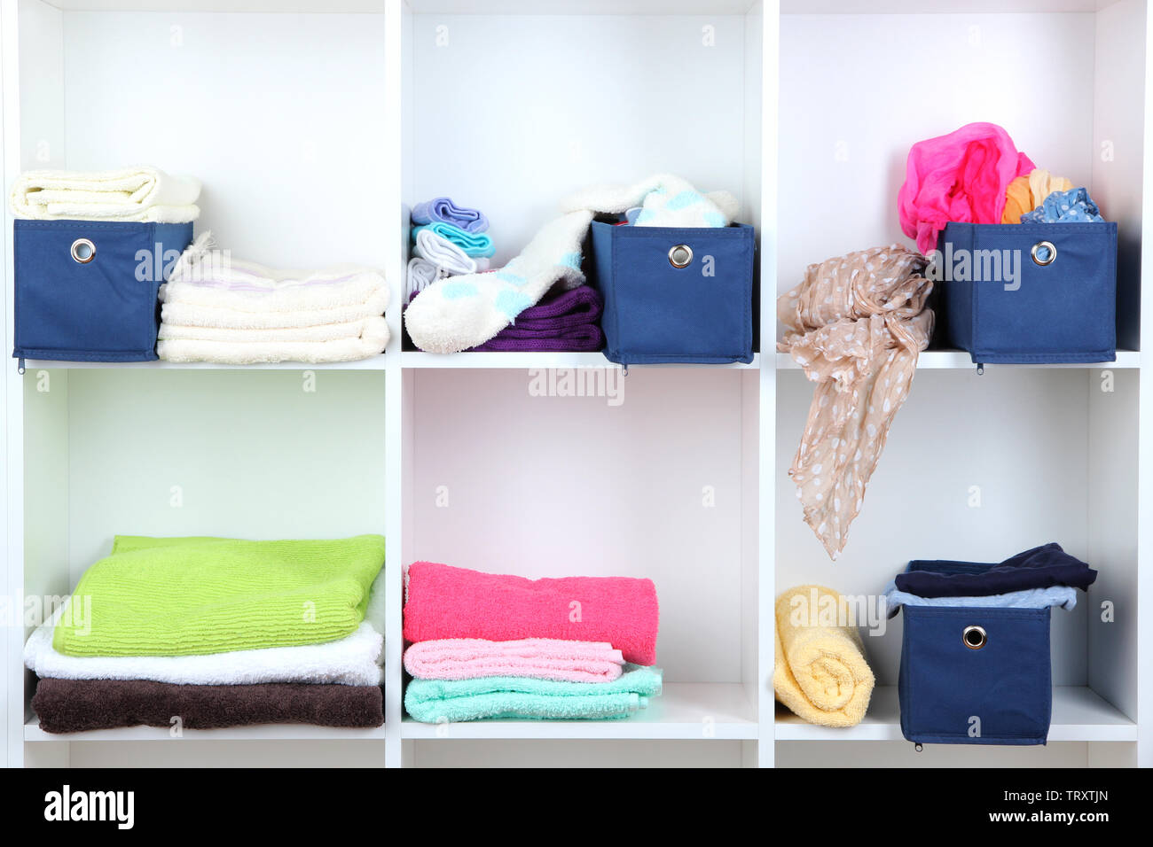 Blue textile boxes with towels and clothes in white shelves Stock Photo ...