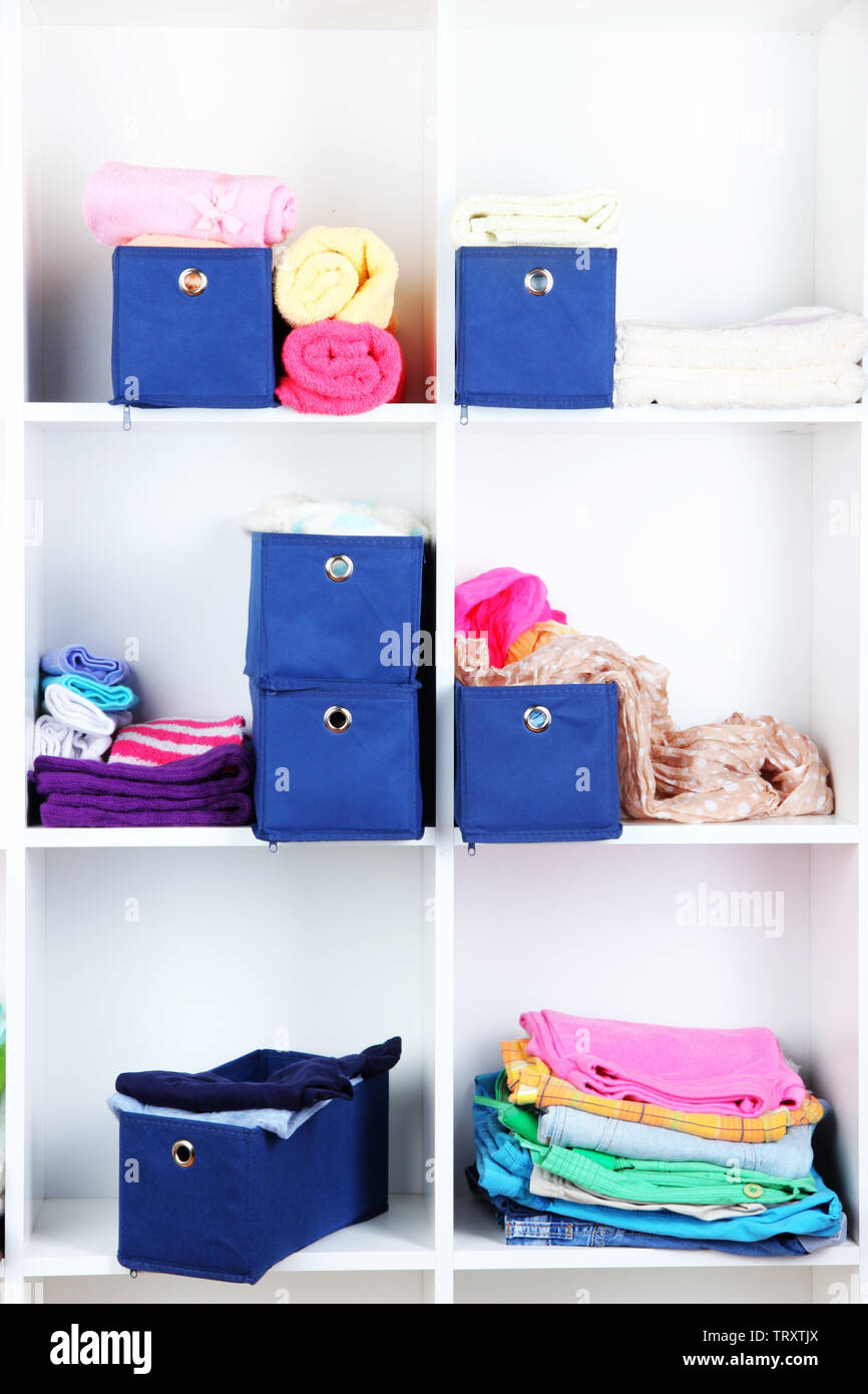 Blue textile boxes with towels and clothes in white shelves Stock Photo ...
