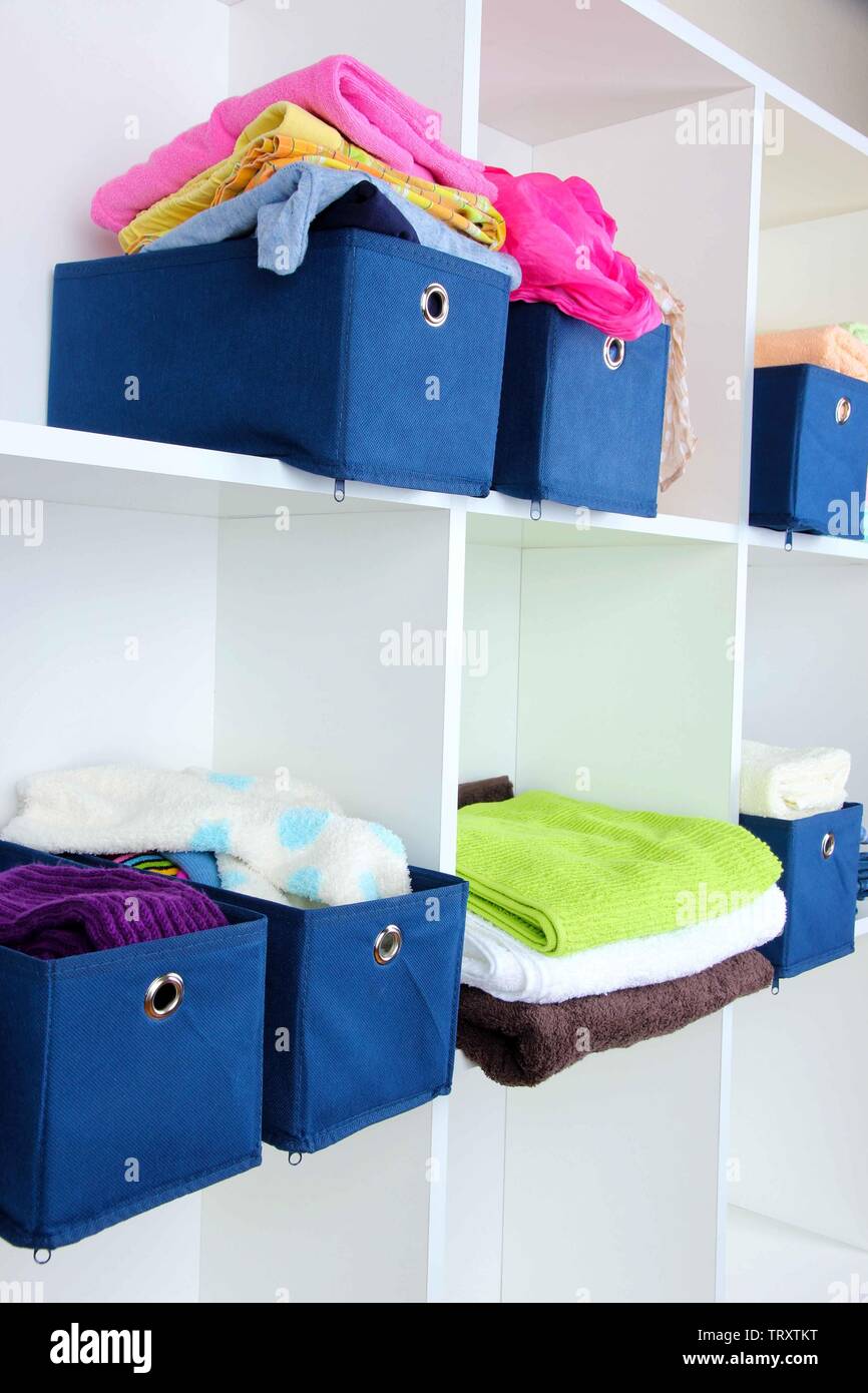 Blue textile boxes with towels and clothes in white shelves Stock Photo ...