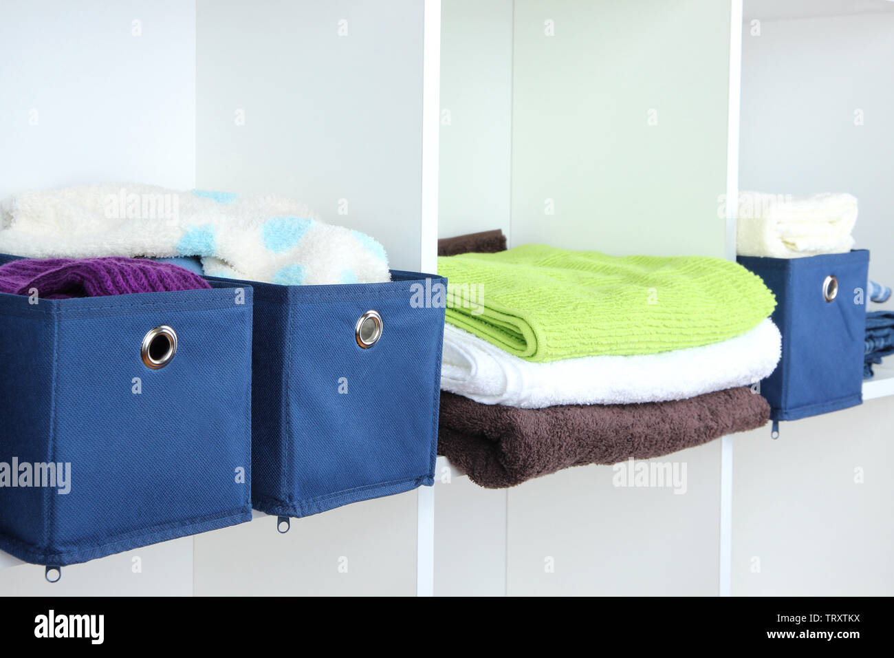 Blue textile boxes with towels and clothes in white shelves Stock Photo ...