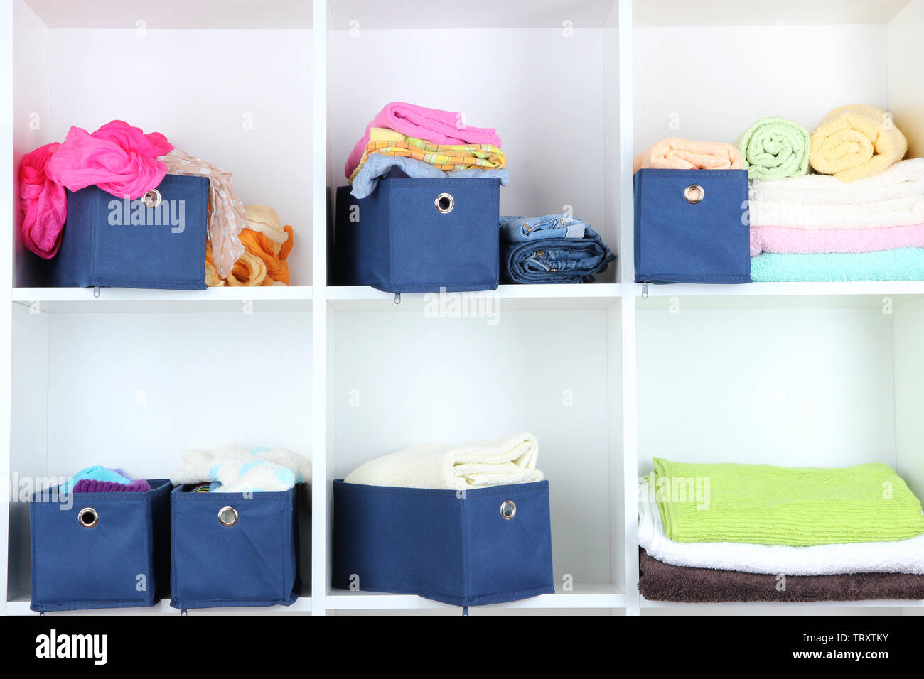 Blue textile boxes with towels and clothes in white shelves Stock Photo ...
