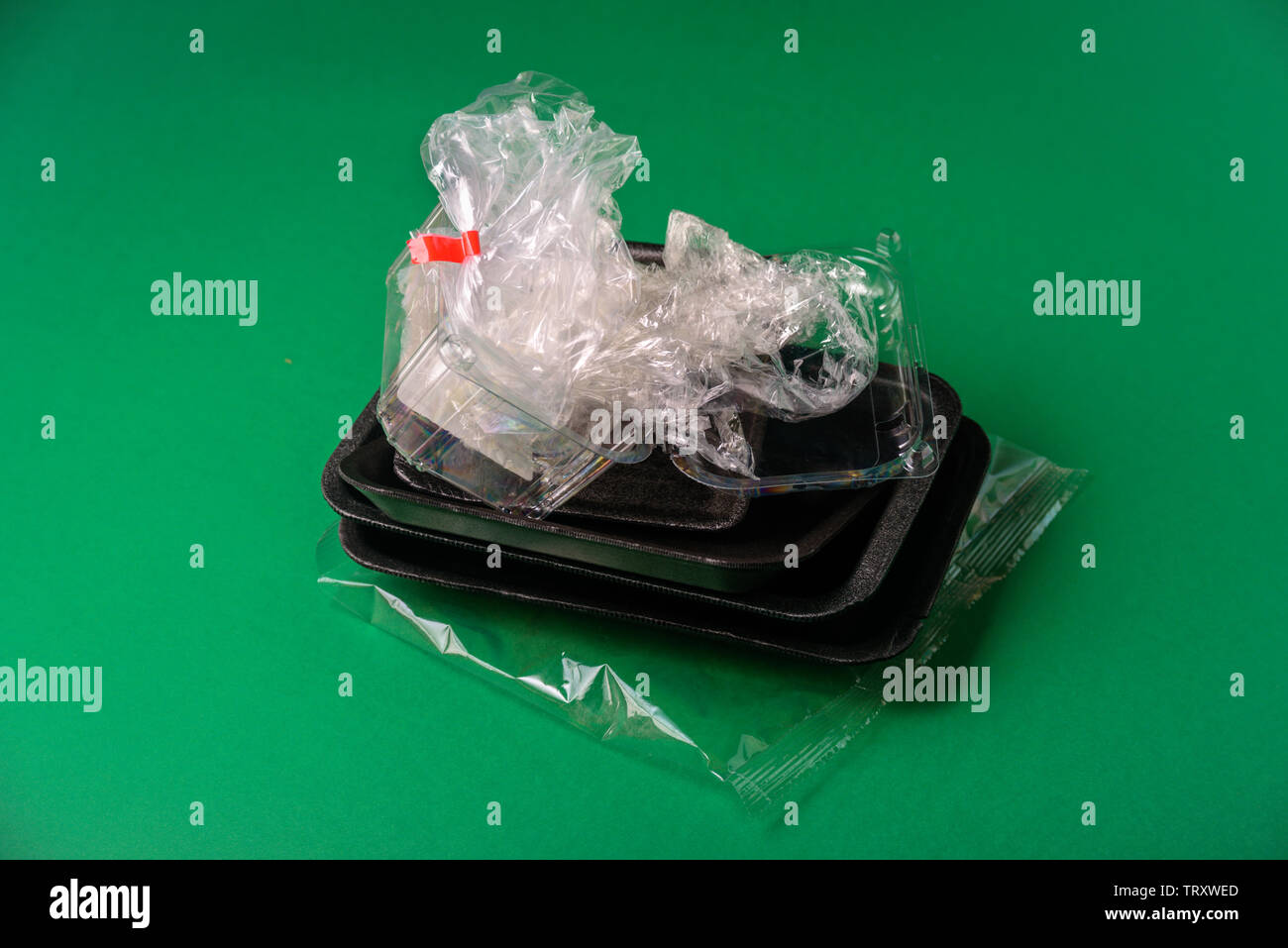 Plastic used disposable food package on green background. Plastic waste ...