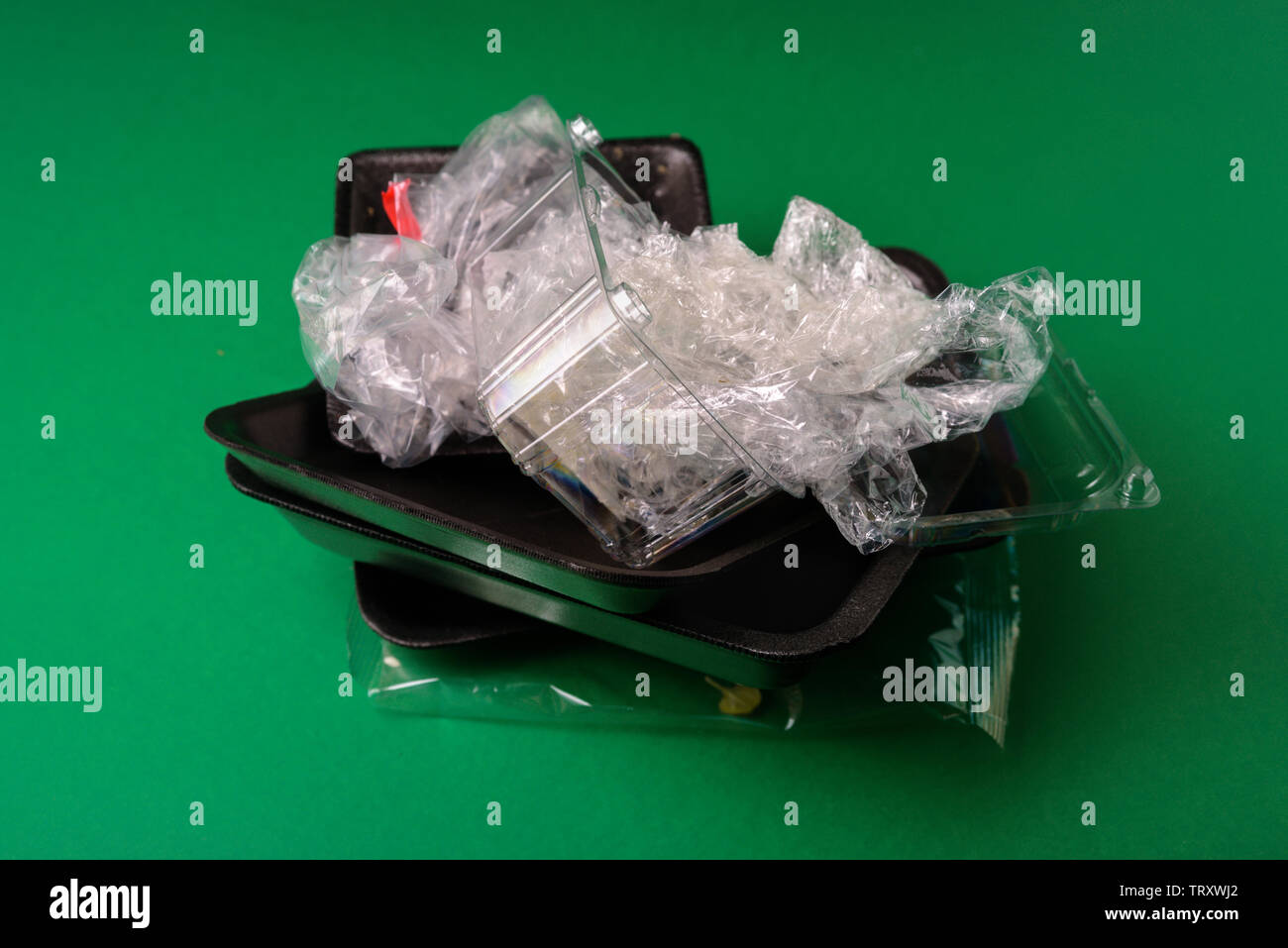 Plastic used disposable food package on green background. Plastic waste ...