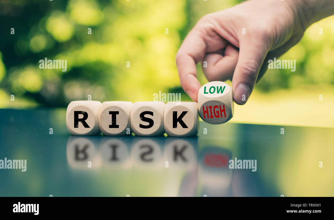 Symbol for reducing a risk. Cubes form the word "RISK" while a hand ...