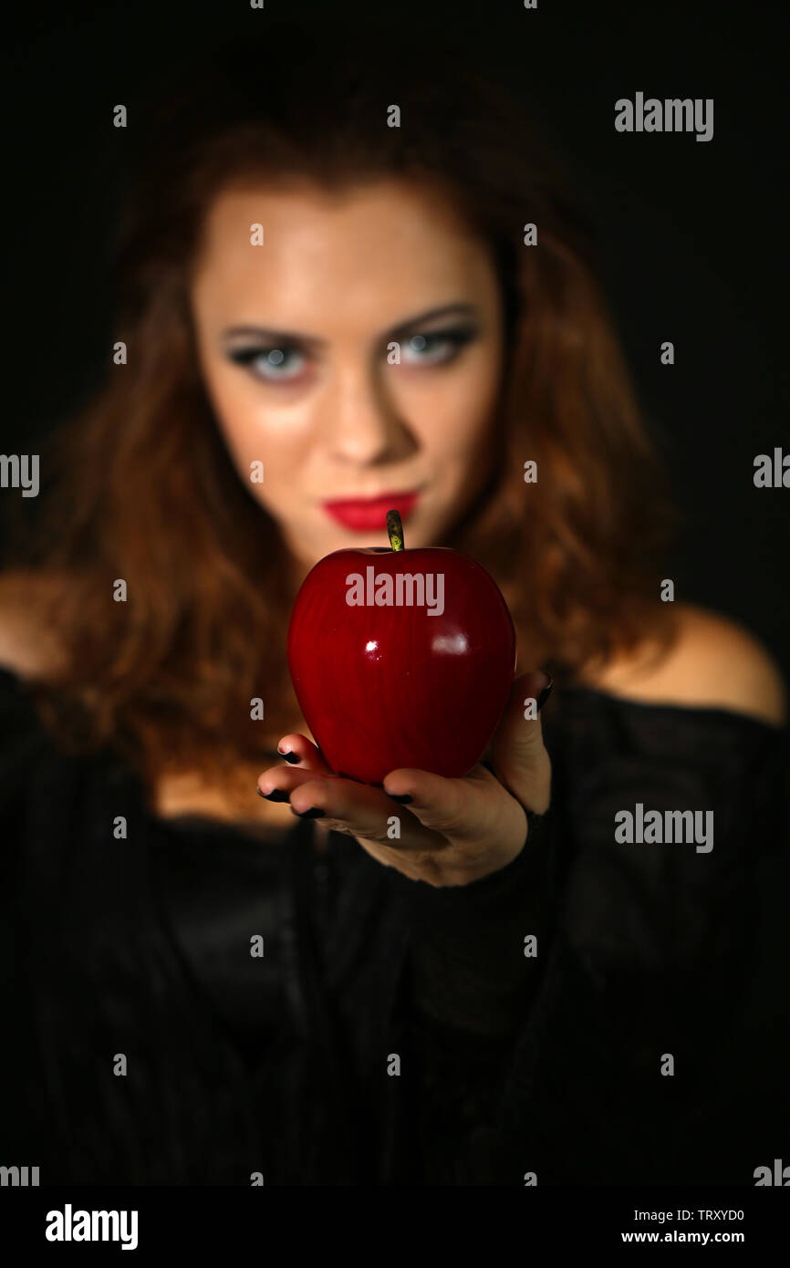 Halloween witch with apple on dark background Stock Photo - Alamy