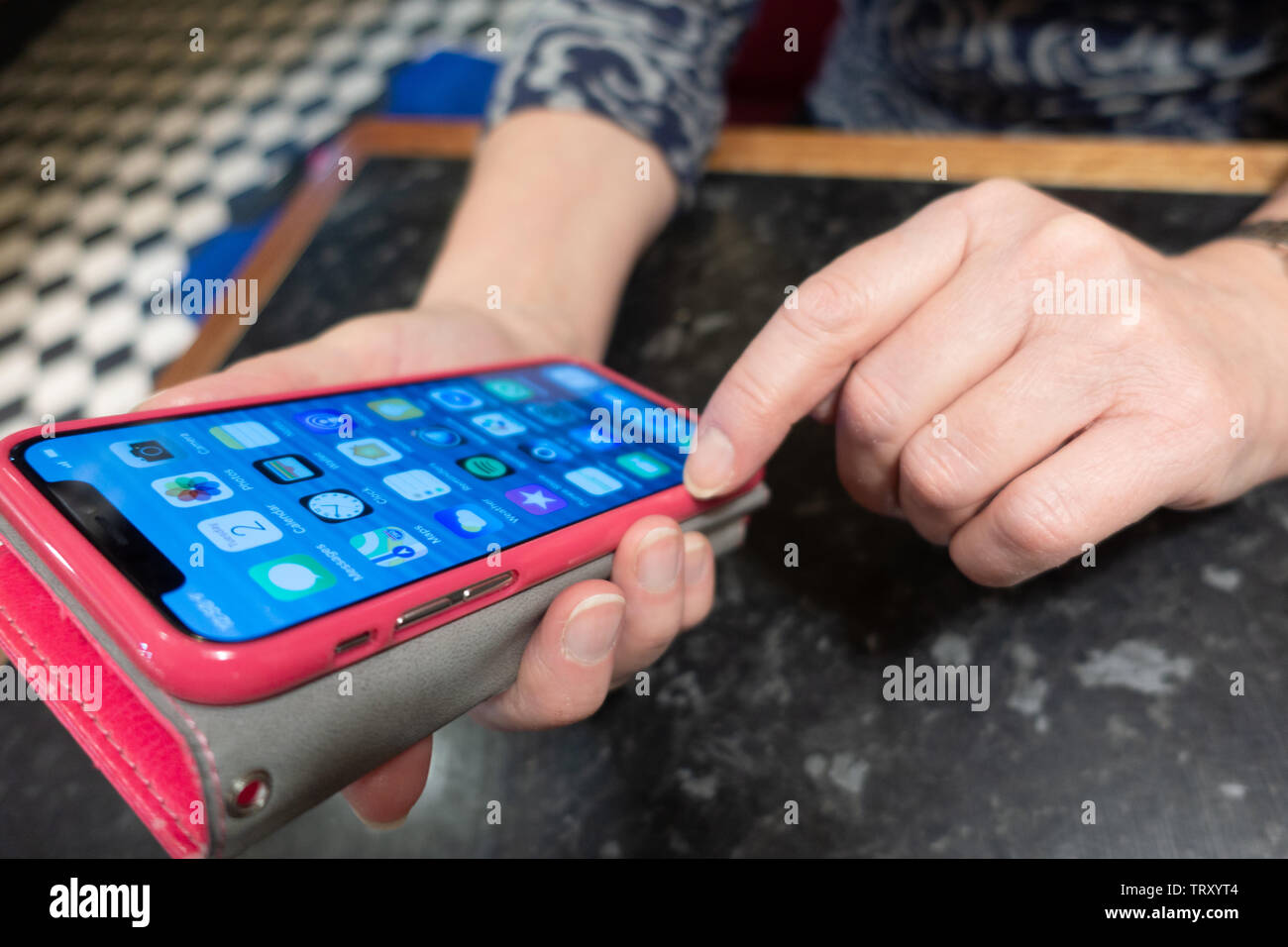 Hands holding a pink apple iphone with finger pointing to an entered ...