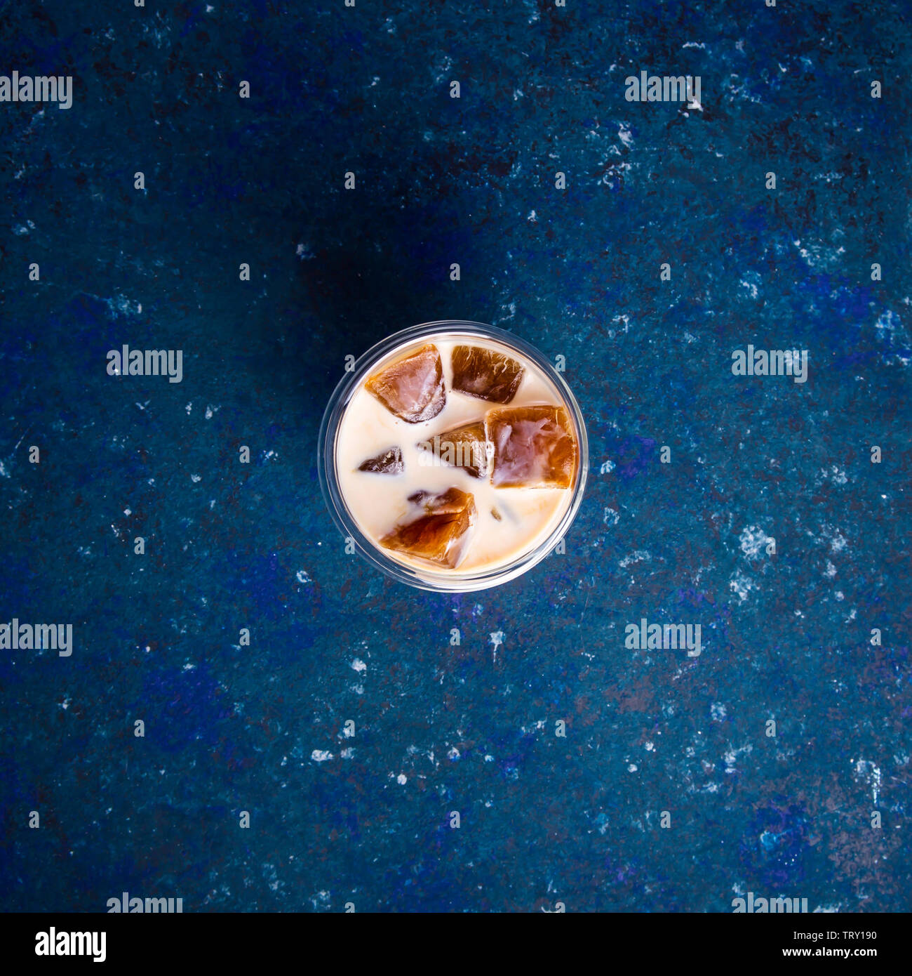 Ice coffee with milk in a modern glass with a double bottom on a blue ...