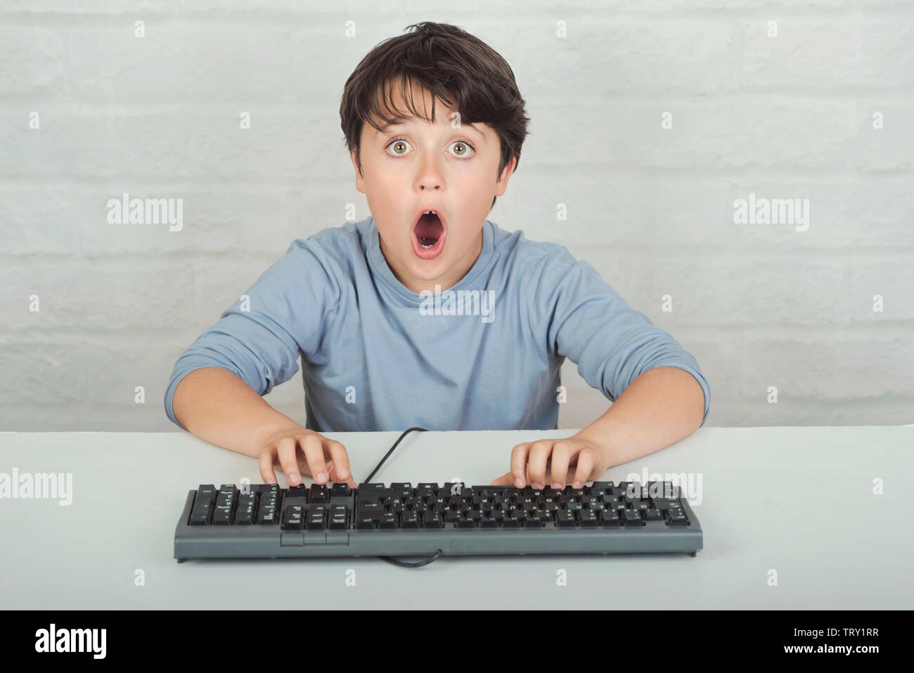 surprised child with keyboard on brick background Stock Photo - Alamy