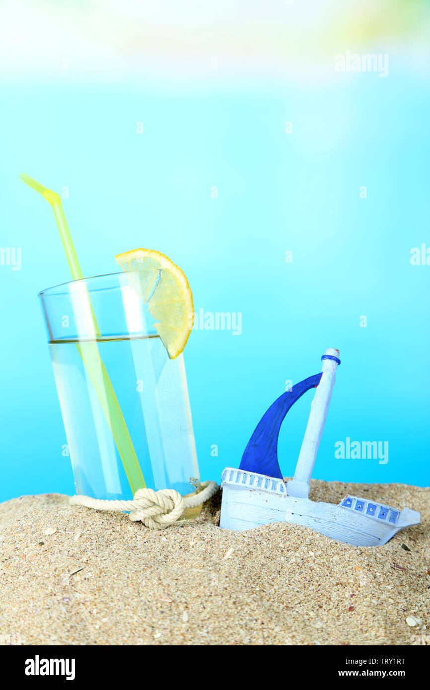 Beach cocktail in sand on blue background Stock Photo - Alamy