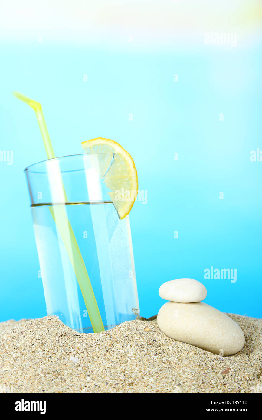Beach cocktail in sand on blue background Stock Photo - Alamy
