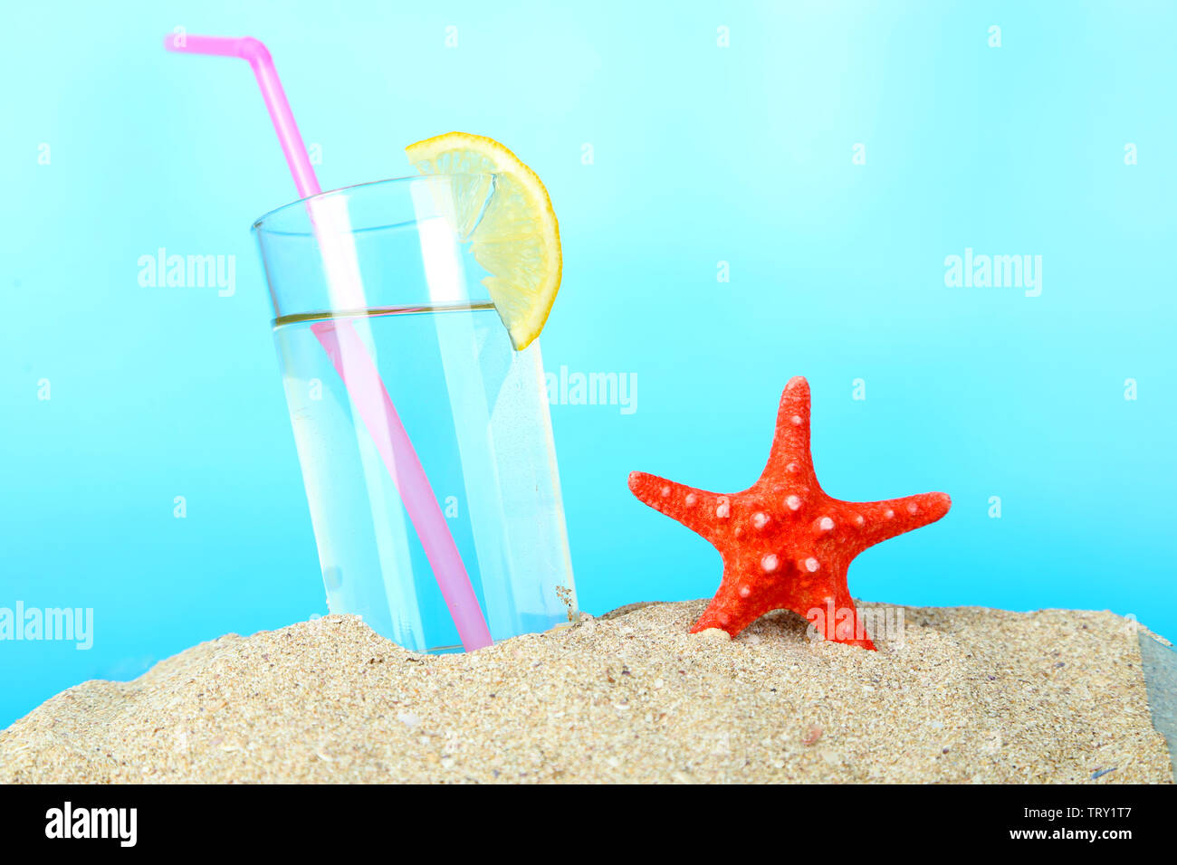 Beach cocktail in sand on blue background Stock Photo - Alamy