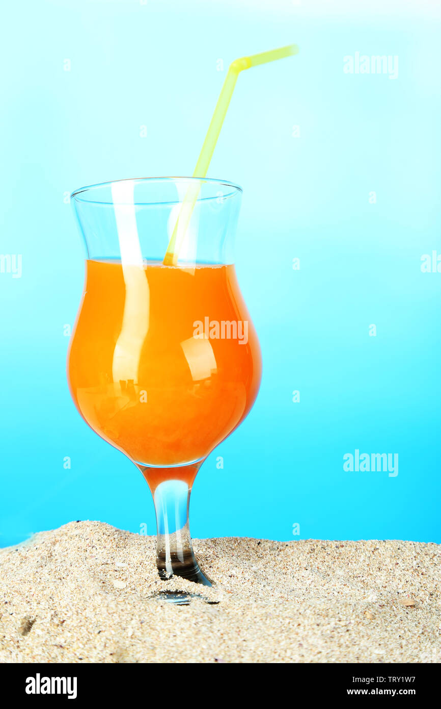 Beach cocktail in sand on blue background Stock Photo - Alamy