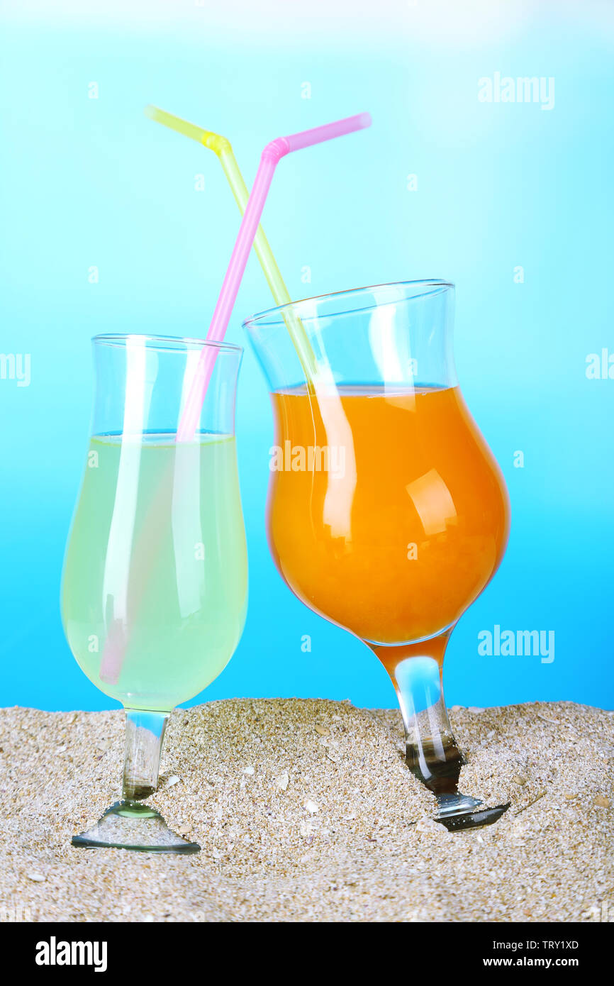 Beach cocktails in sand on blue background Stock Photo - Alamy