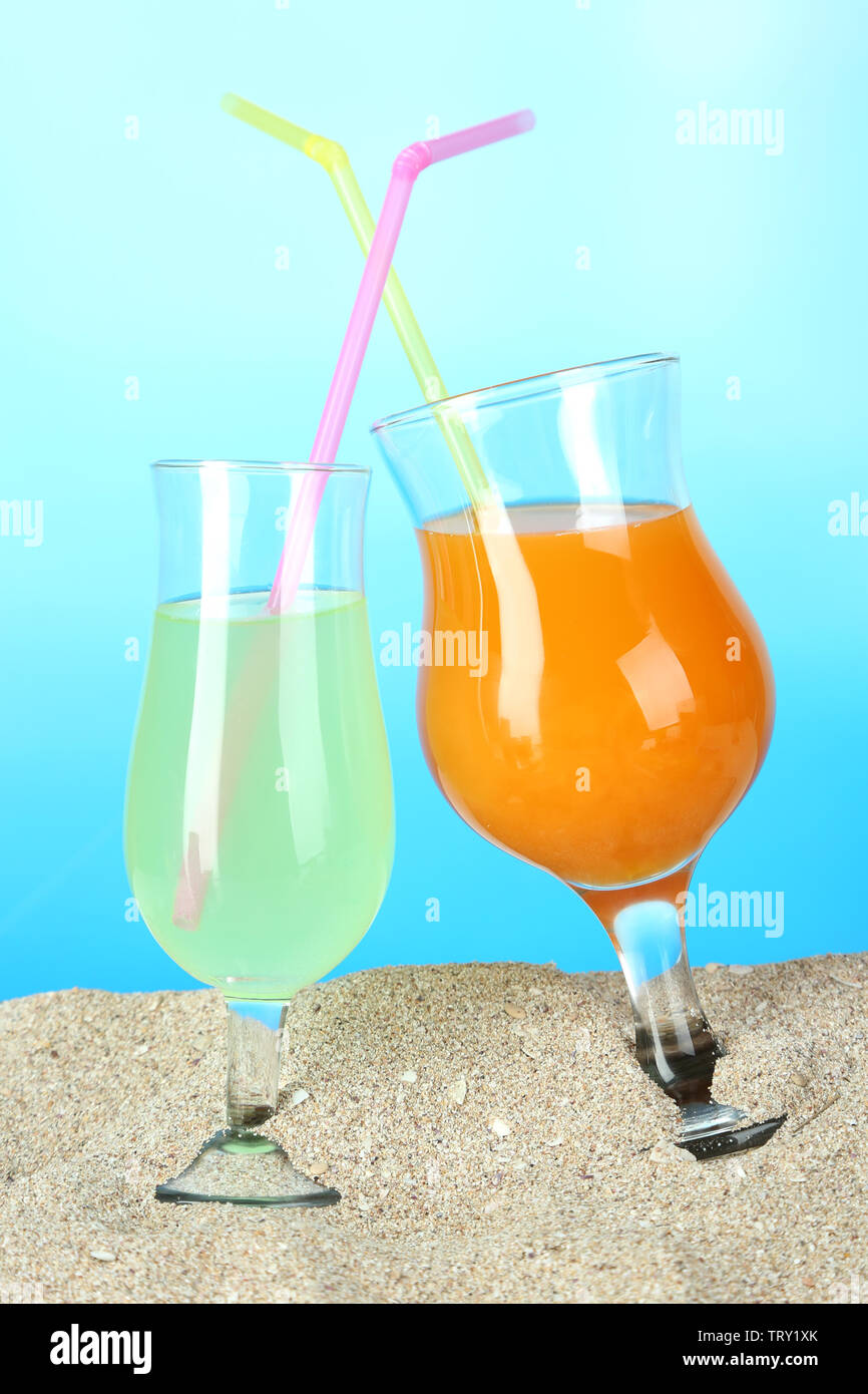 Beach cocktails in sand on blue background Stock Photo - Alamy