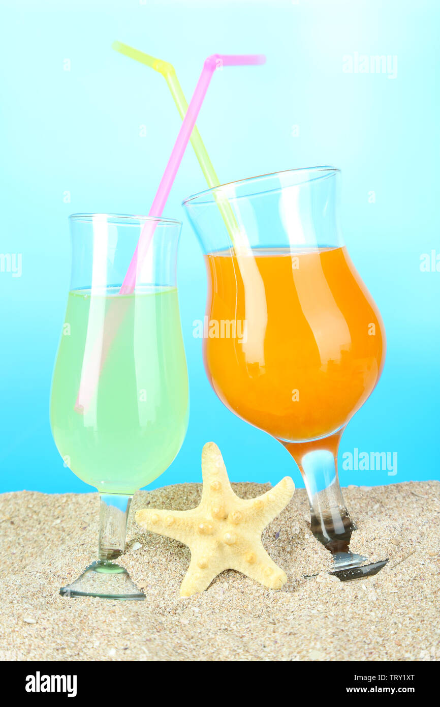 Beach cocktails in sand on blue background Stock Photo - Alamy