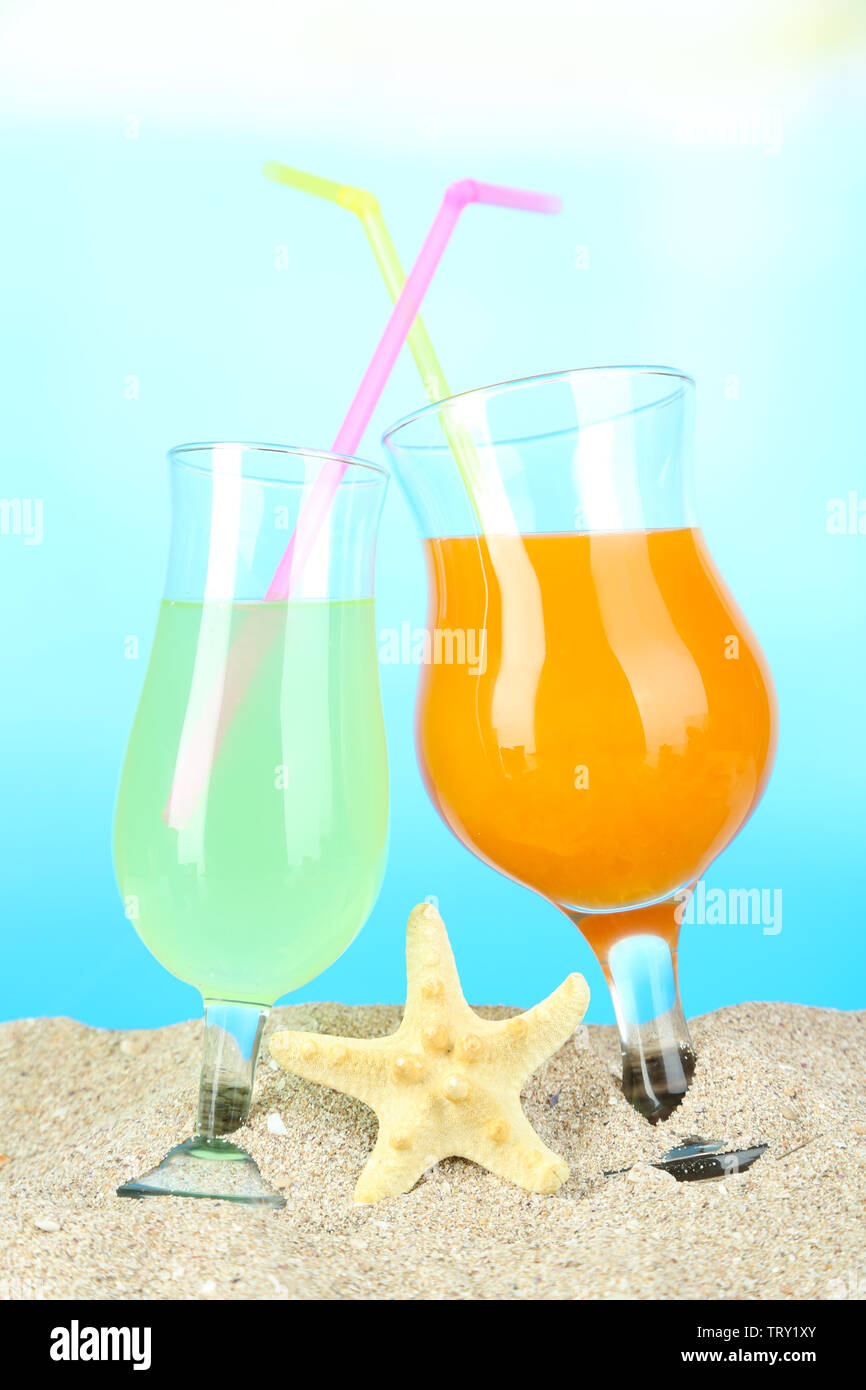 Beach cocktails in sand on blue background Stock Photo - Alamy