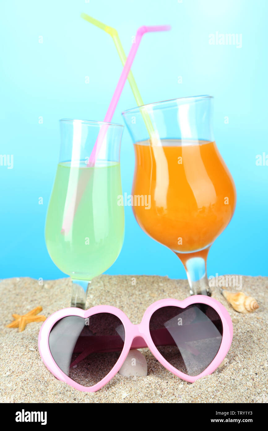 Beach cocktails in sand on blue background Stock Photo - Alamy