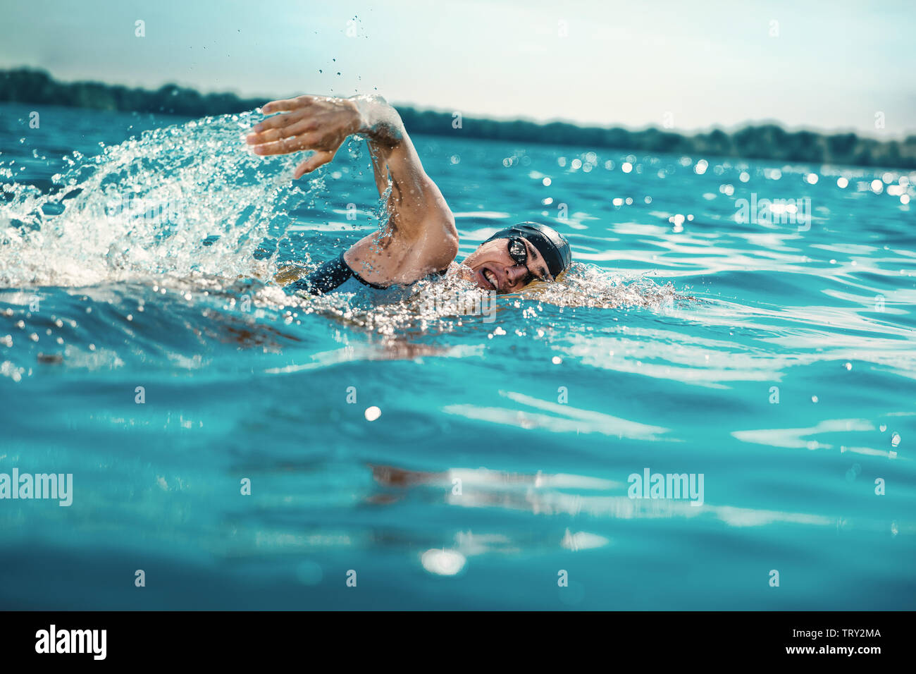 Professional triathlete swimming in river's open water. Man wearing ...