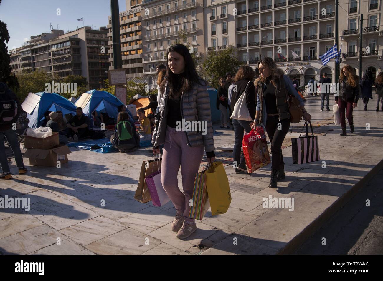 Greek women after shopping pass by refugees and their tents. Refugees ...