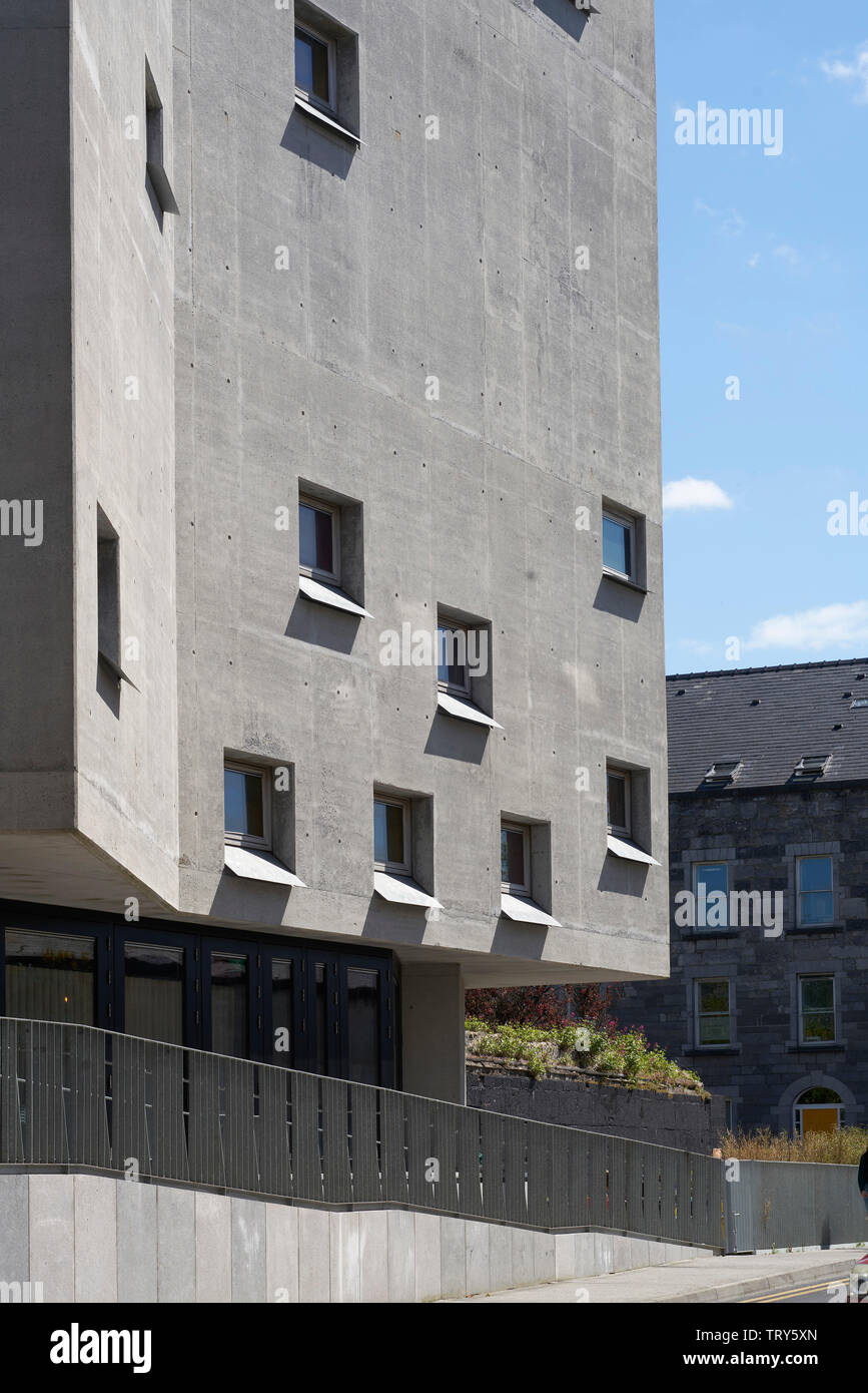 Cast-concrete facade with recessed square windows and entrance ramp ...