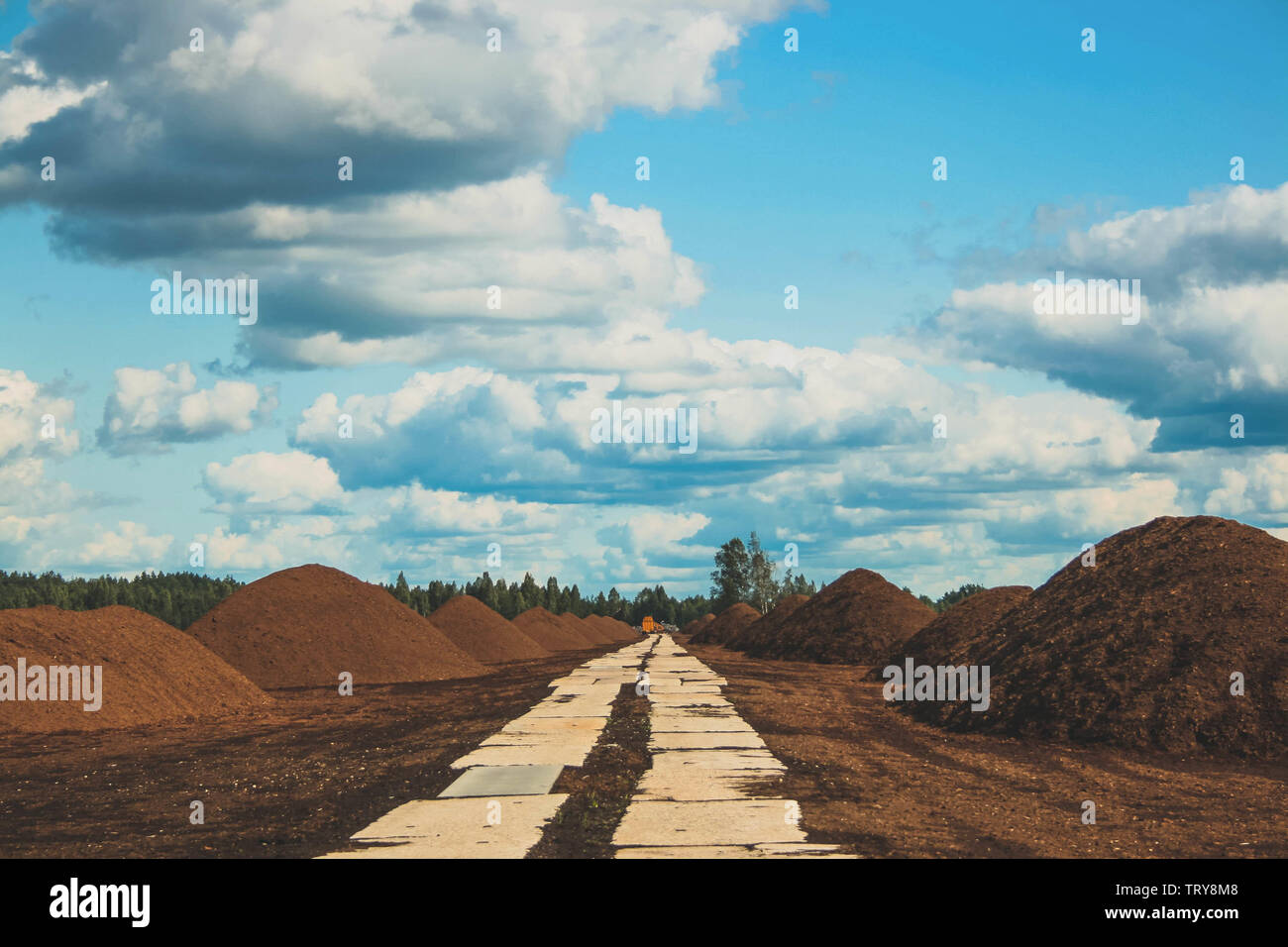 Concrete path leading through piles of peat on a sunny summer day Stock ...