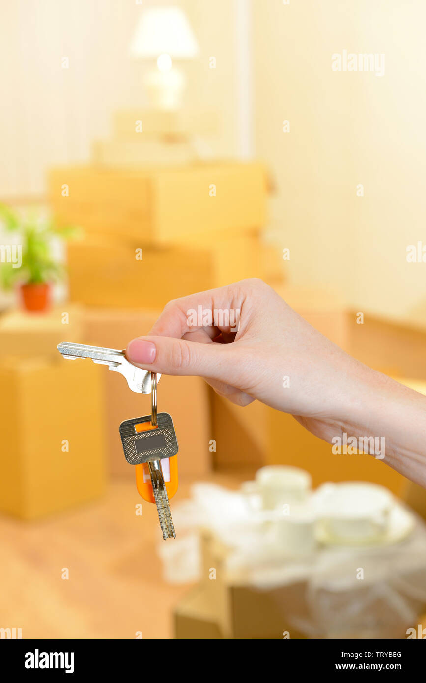 Female hand with keys ob stack of cartons background: moving house ...