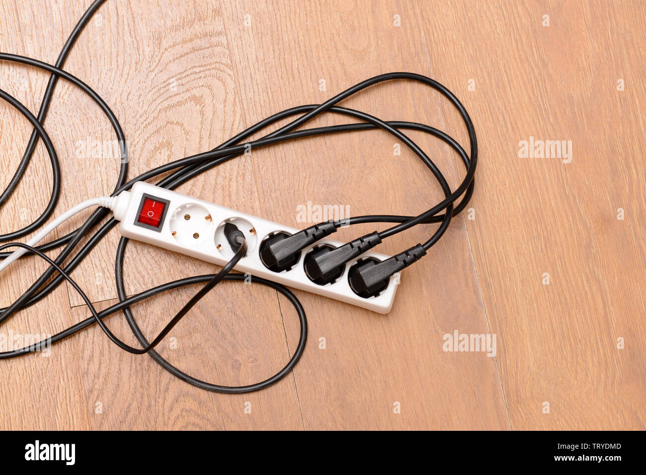 Overloaded power board, on wooden floor background Stock Photo - Alamy