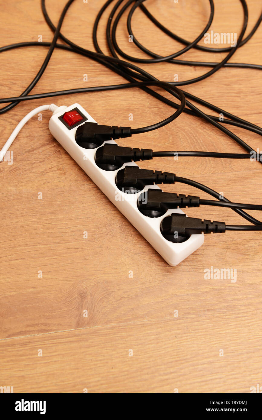 Overloaded power board, on wooden floor background Stock Photo - Alamy