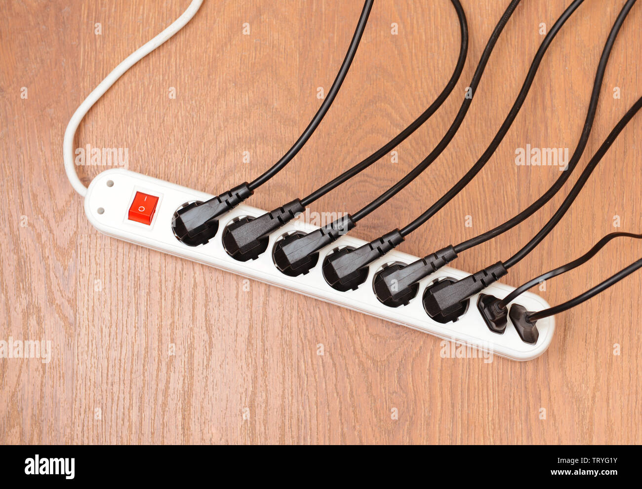 Overloaded power board, on wooden floor background Stock Photo - Alamy