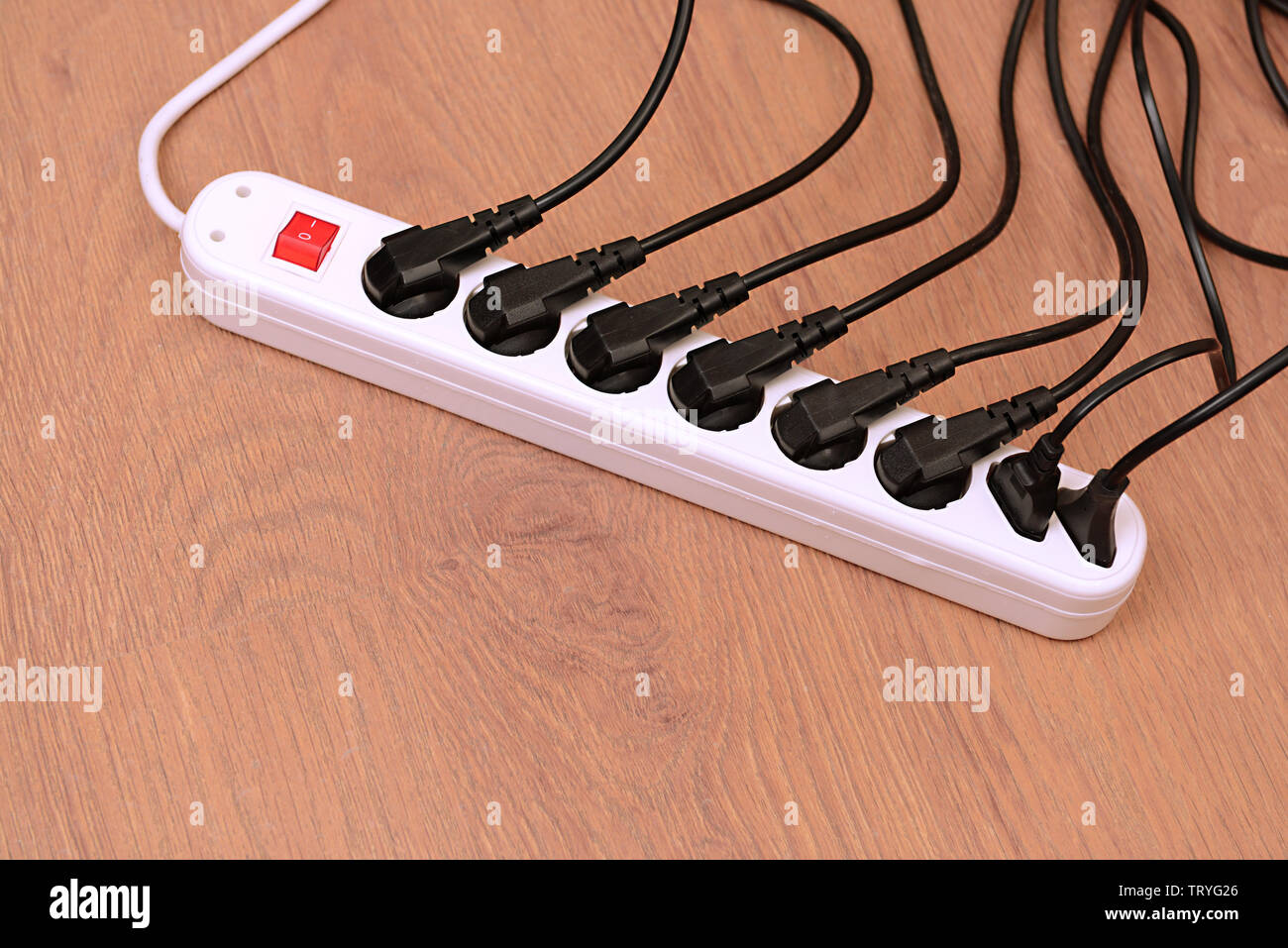 Overloaded power board, on wooden floor background Stock Photo - Alamy