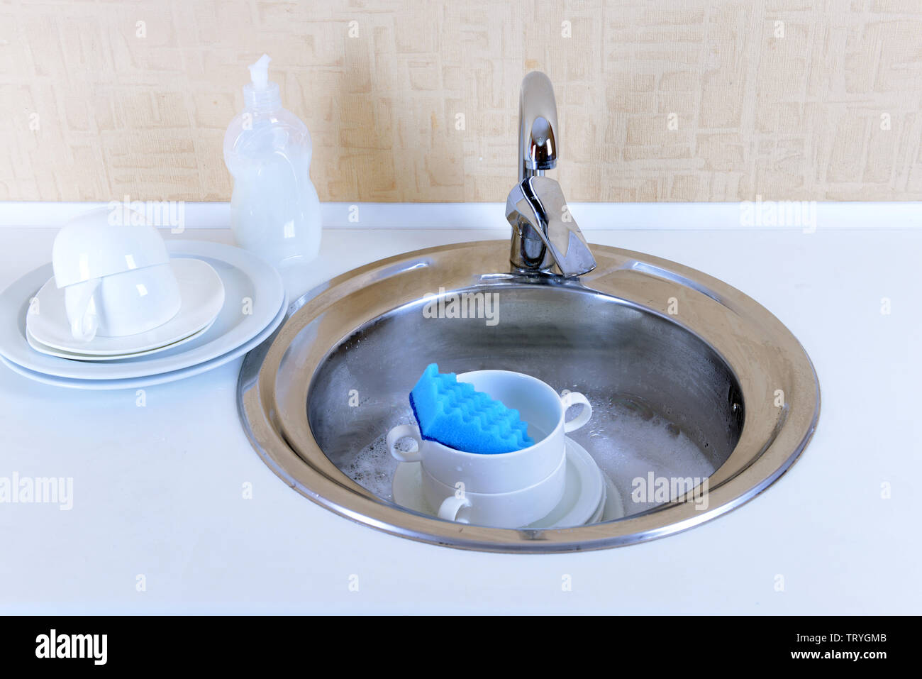Stack of dishes soaking in kitchen sink Stock Photo - Alamy