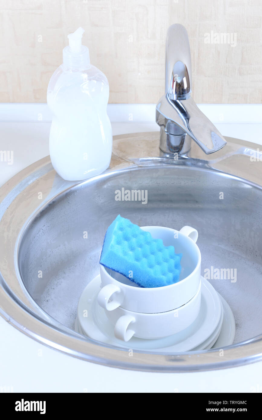 Stack of dishes soaking in kitchen sink Stock Photo - Alamy