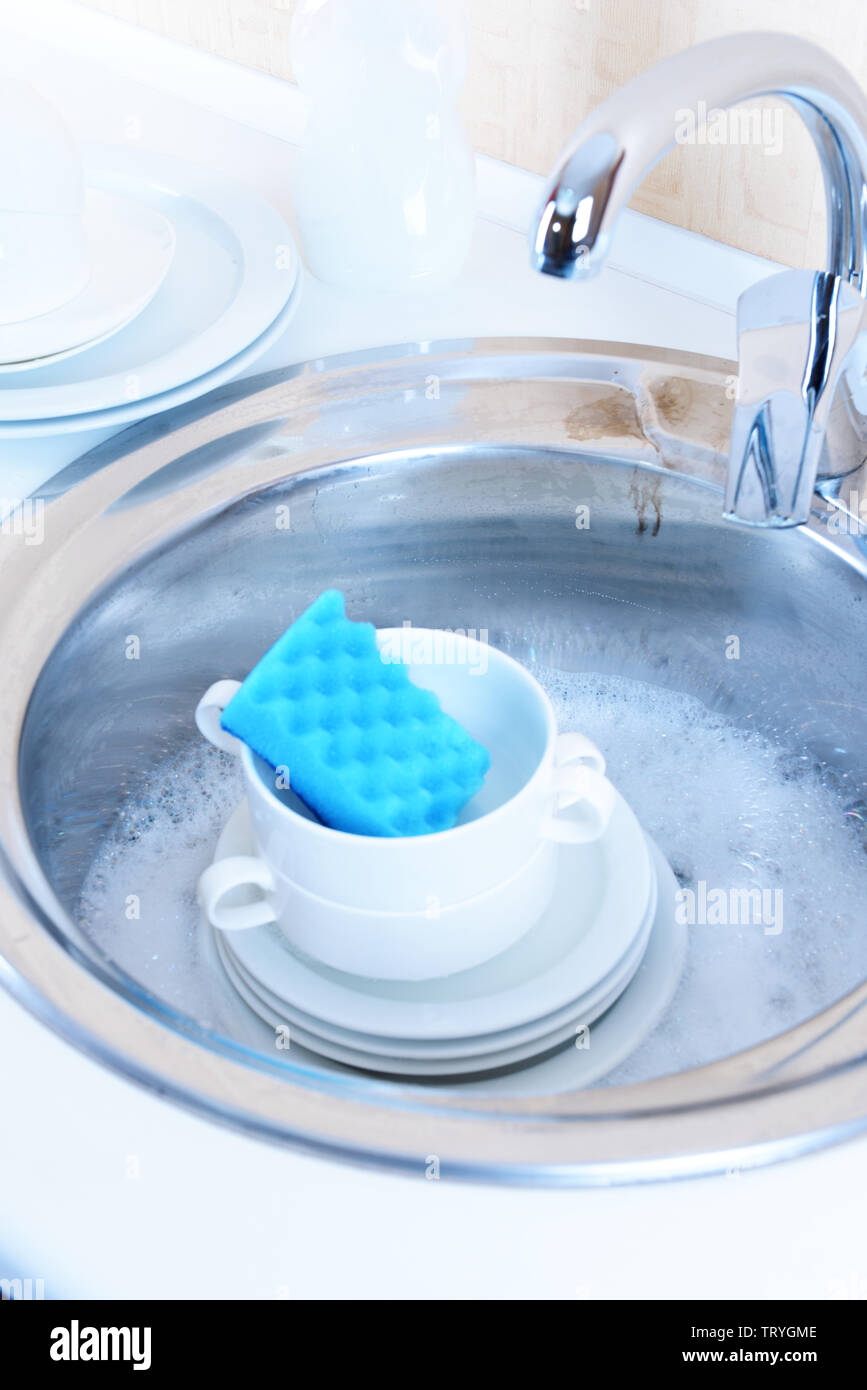 Stack of dishes soaking in kitchen sink Stock Photo - Alamy