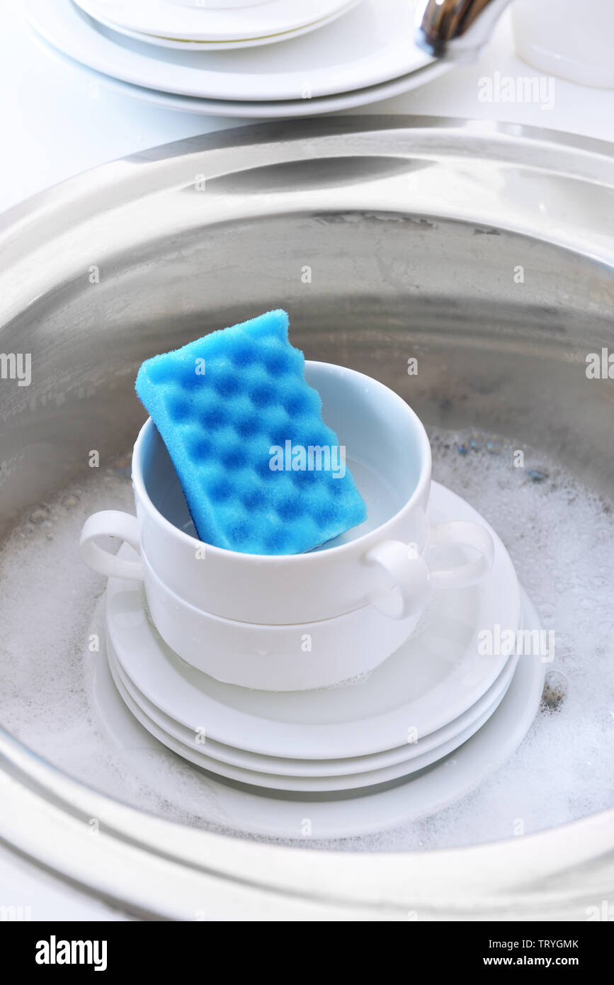 Stack of dishes soaking in kitchen sink Stock Photo - Alamy