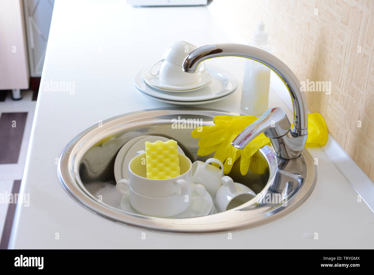 Stack of dishes soaking in kitchen sink Stock Photo - Alamy