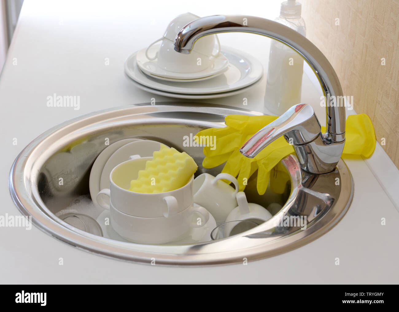 Stack of dishes soaking in kitchen sink Stock Photo - Alamy