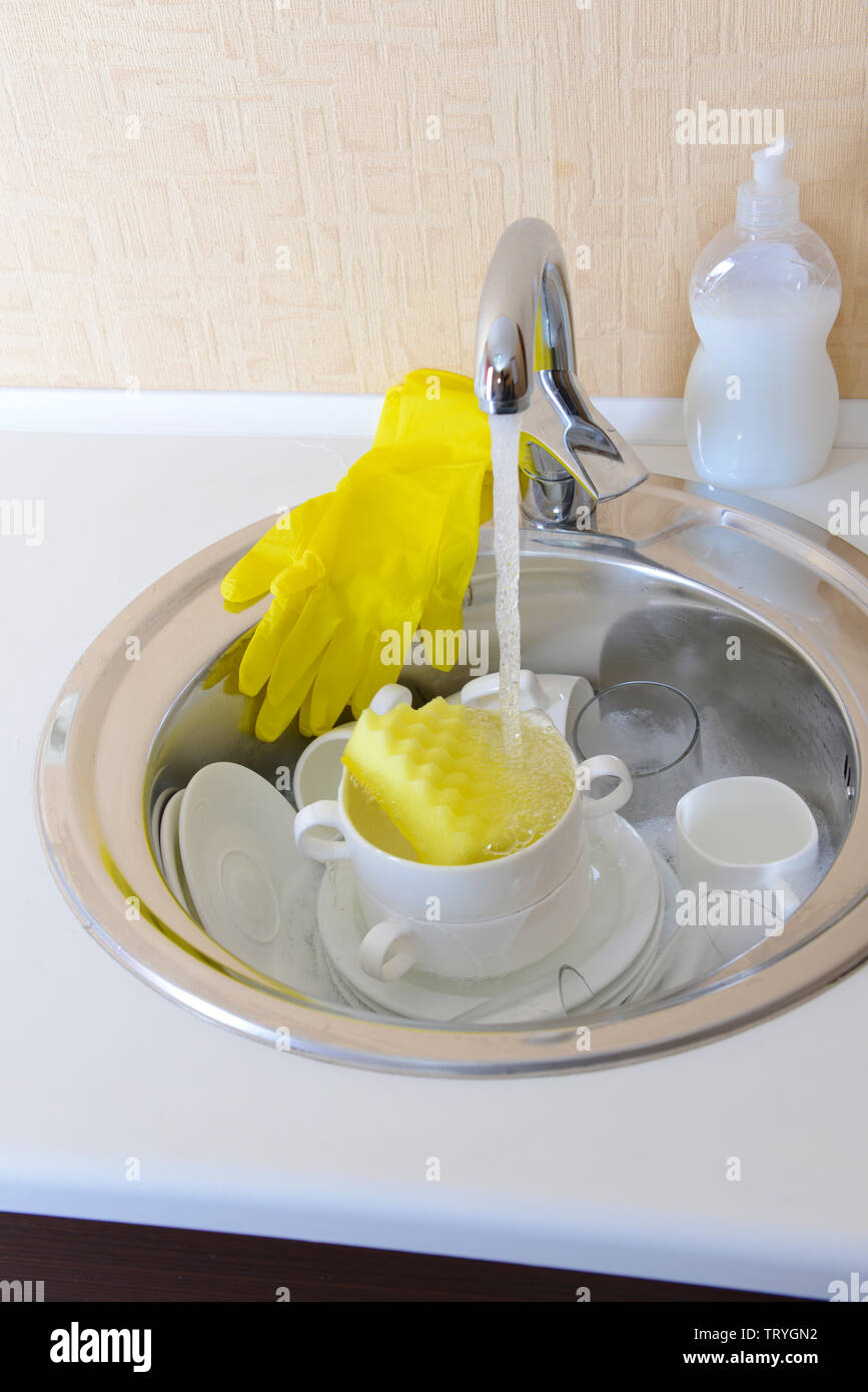 Stack of dishes soaking in kitchen sink Stock Photo - Alamy