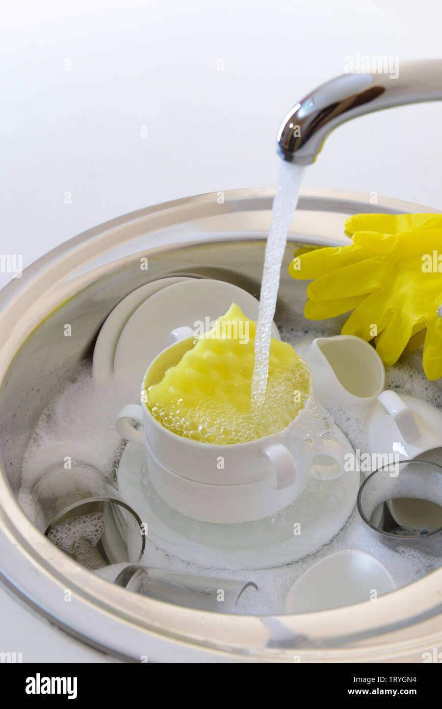 Stack of dishes soaking in kitchen sink Stock Photo - Alamy