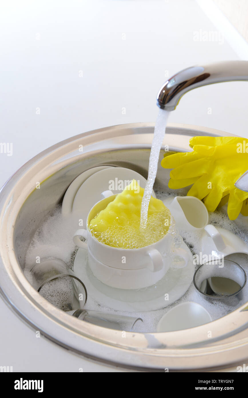 Stack of dishes soaking in kitchen sink Stock Photo - Alamy