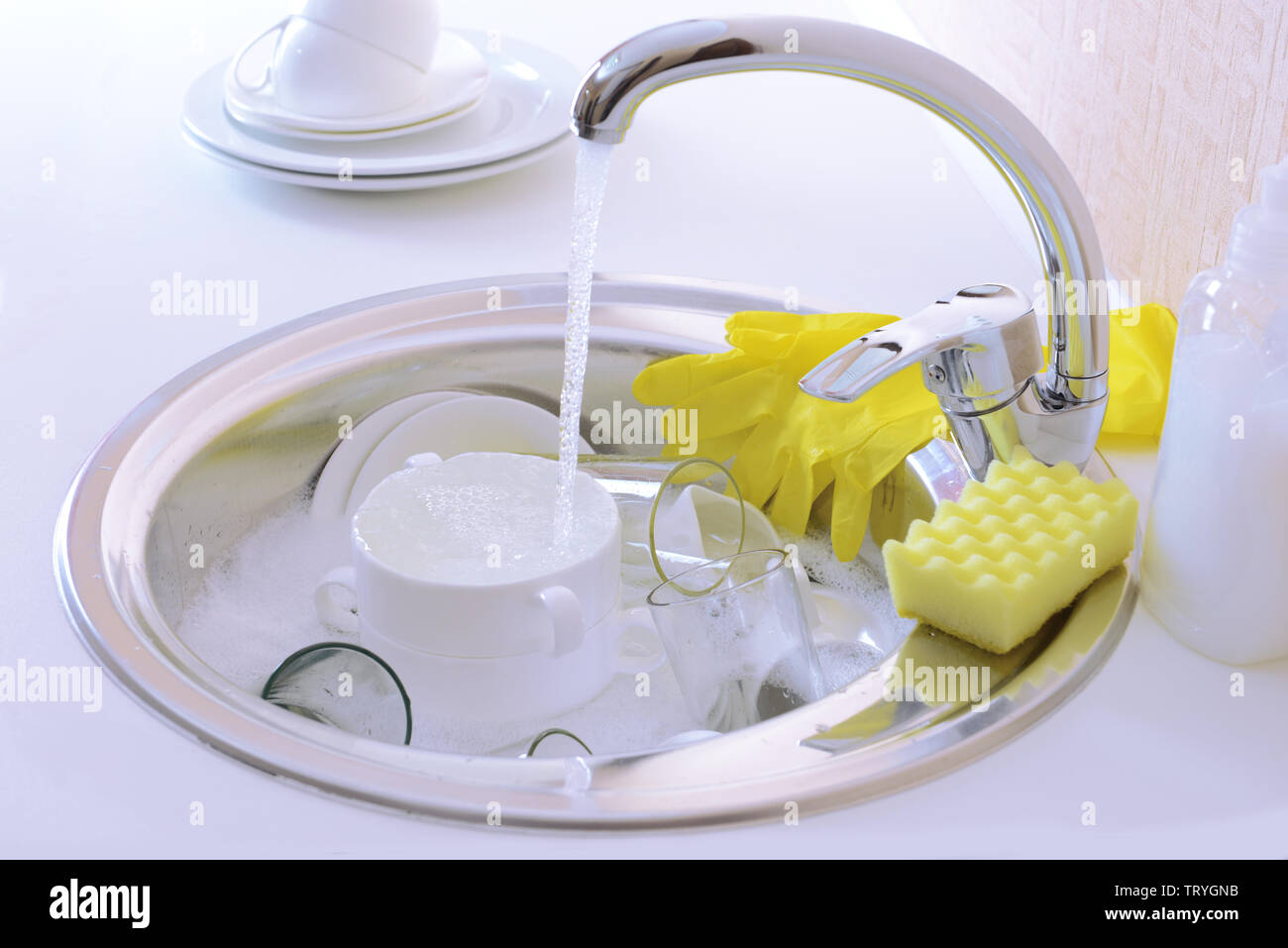 Stack of dishes soaking in kitchen sink Stock Photo - Alamy