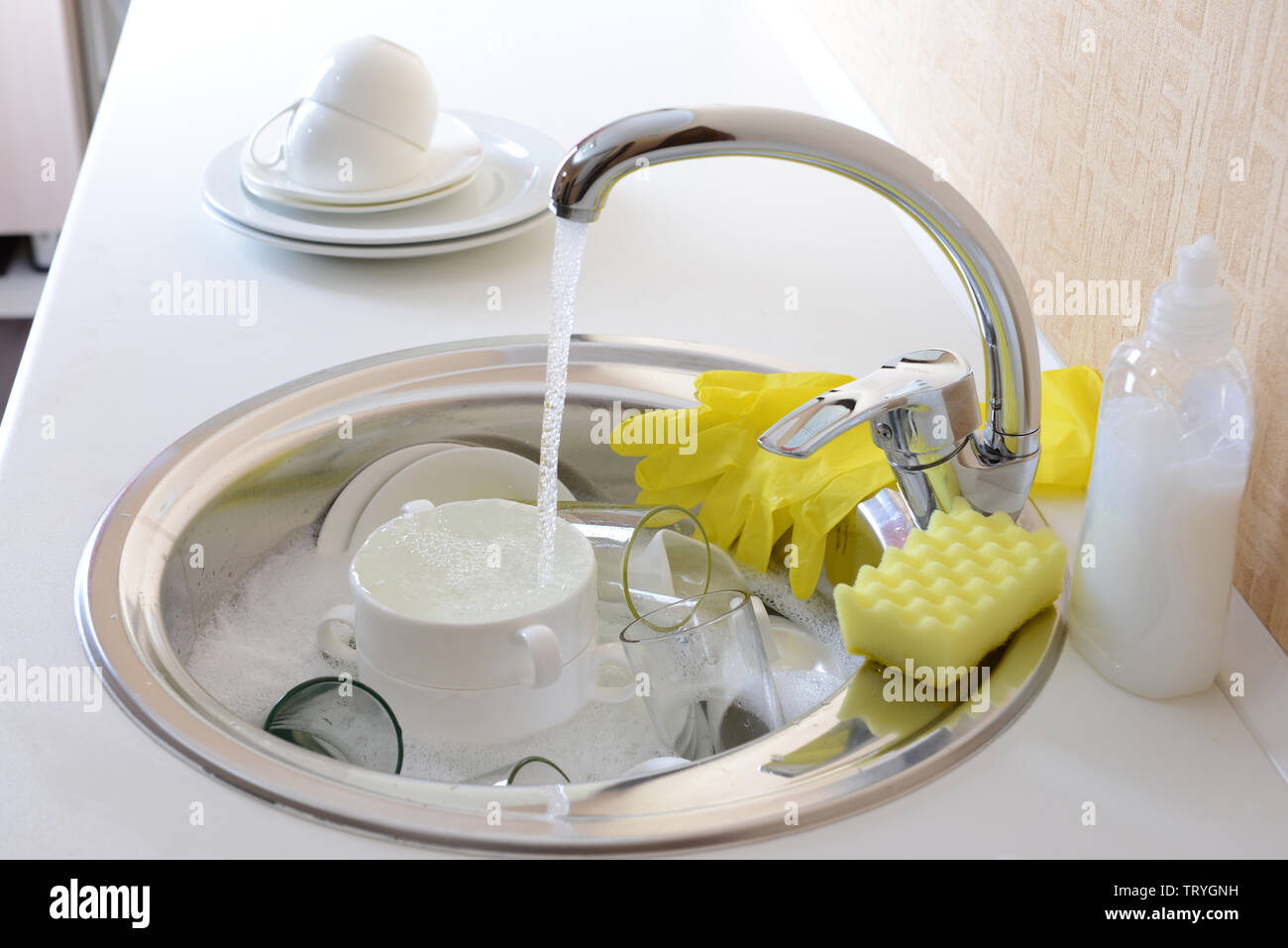 Stack of dishes soaking in kitchen sink Stock Photo - Alamy