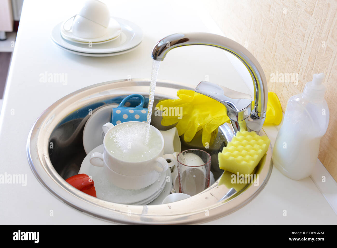 Stack of dishes soaking in kitchen sink Stock Photo - Alamy