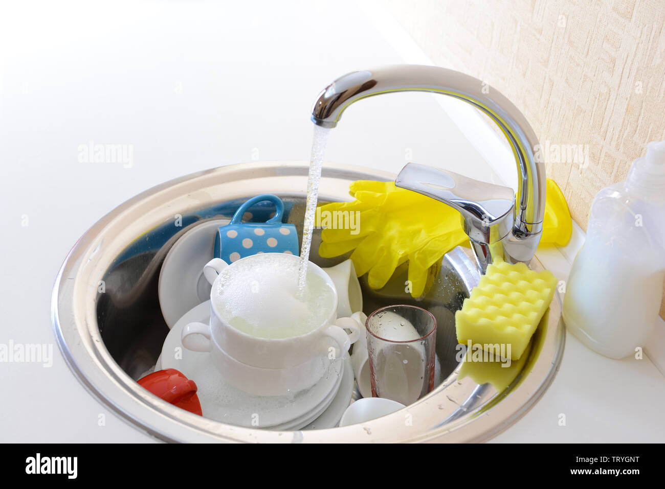 Stack of dishes soaking in kitchen sink Stock Photo - Alamy