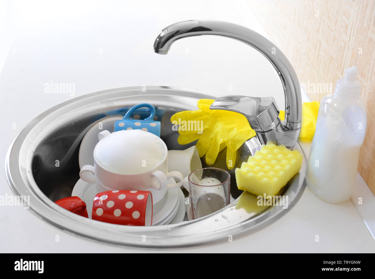 Stack of dishes soaking in kitchen sink Stock Photo - Alamy