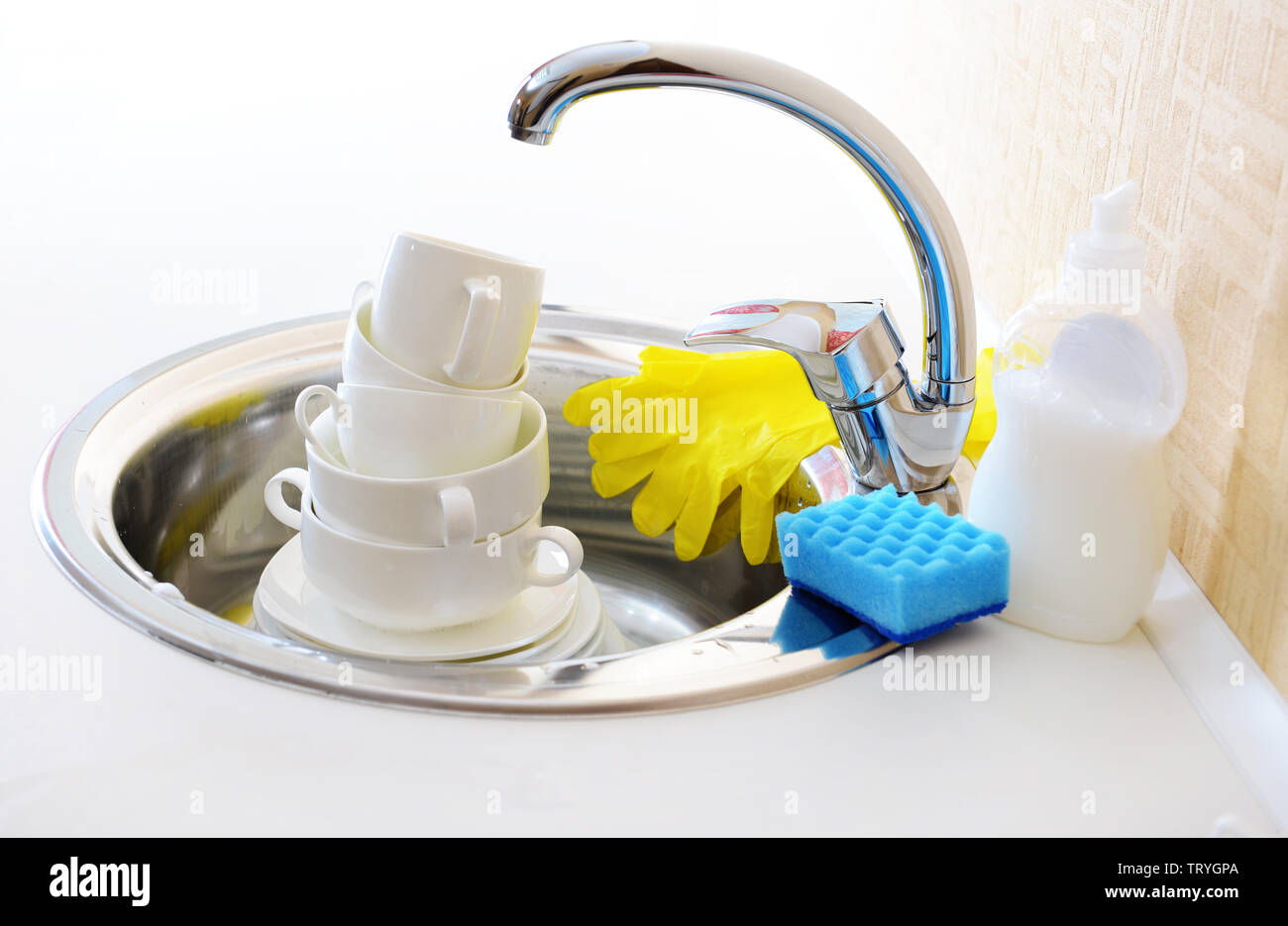 Stack of dishes soaking in kitchen sink Stock Photo - Alamy