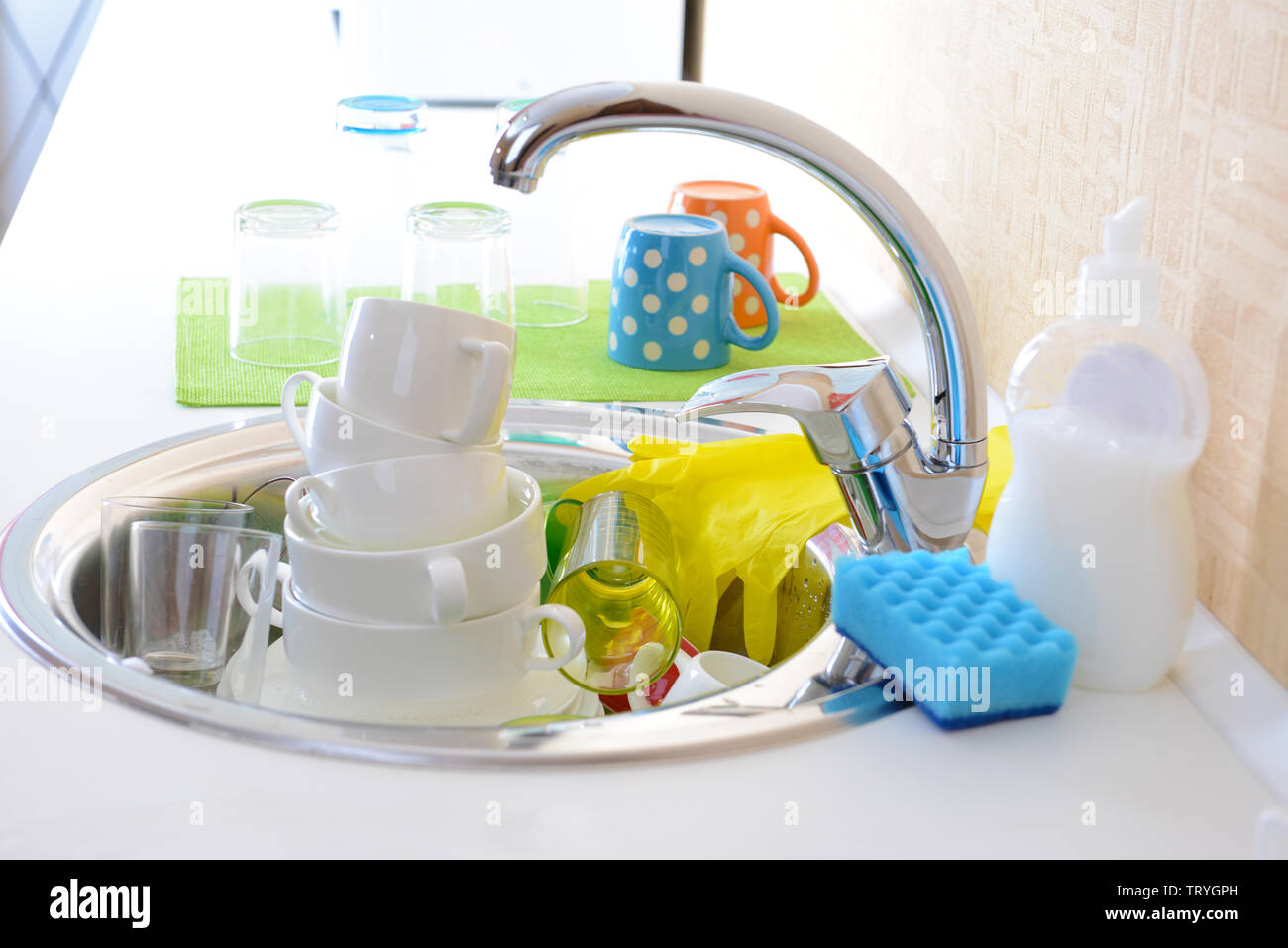 Stack of dishes soaking in kitchen sink Stock Photo - Alamy