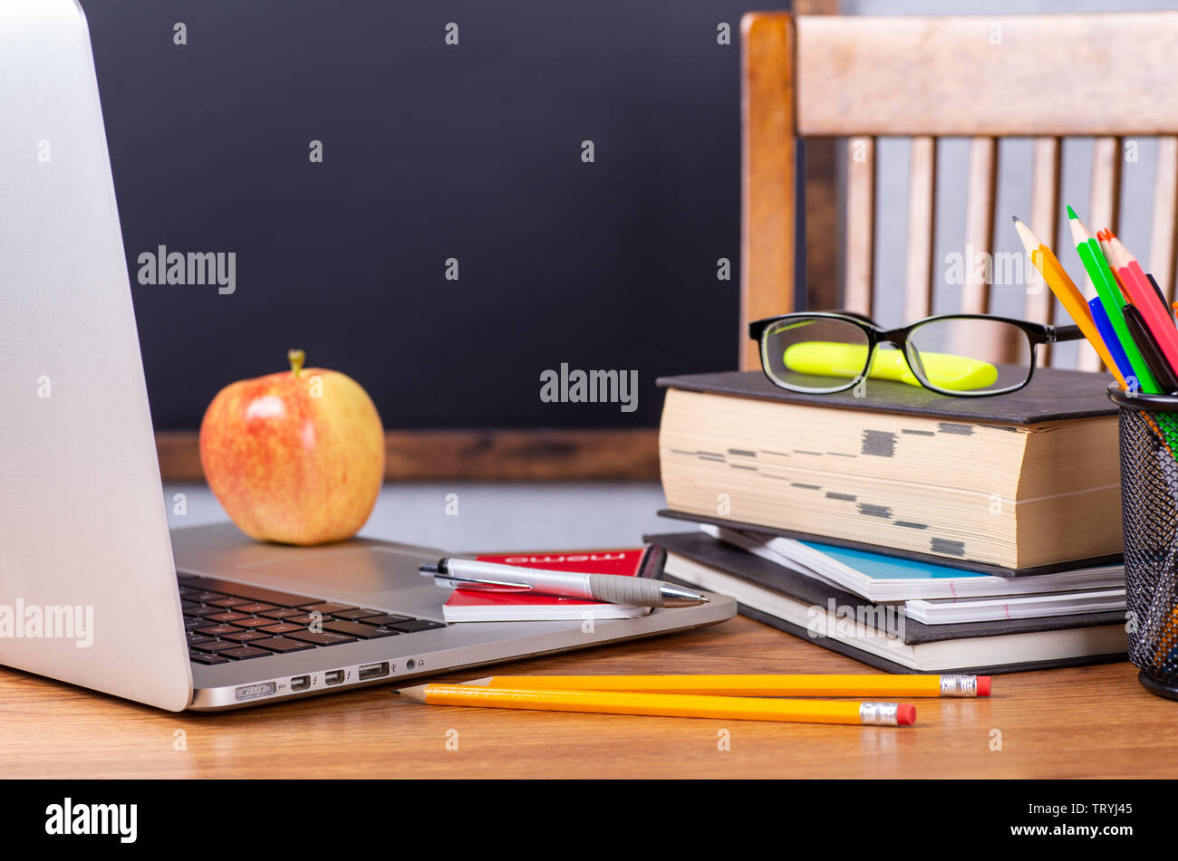 Closeup of a desk with various school items and a blank blackboard in ...
